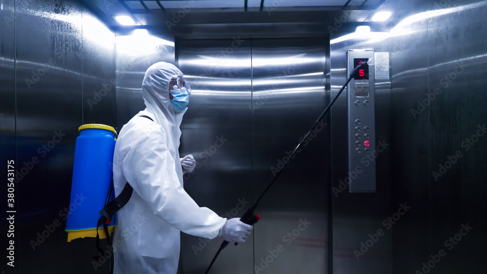 Worker in personal protective equipment (ppe) suit cleaning in building ...