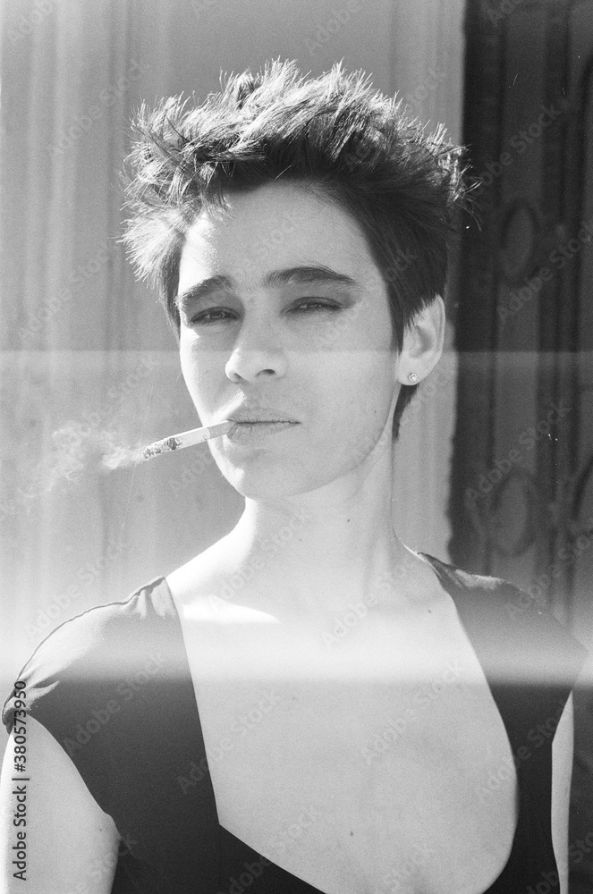 A film portrait of a beautiful young woman smoking cigarette in the ...