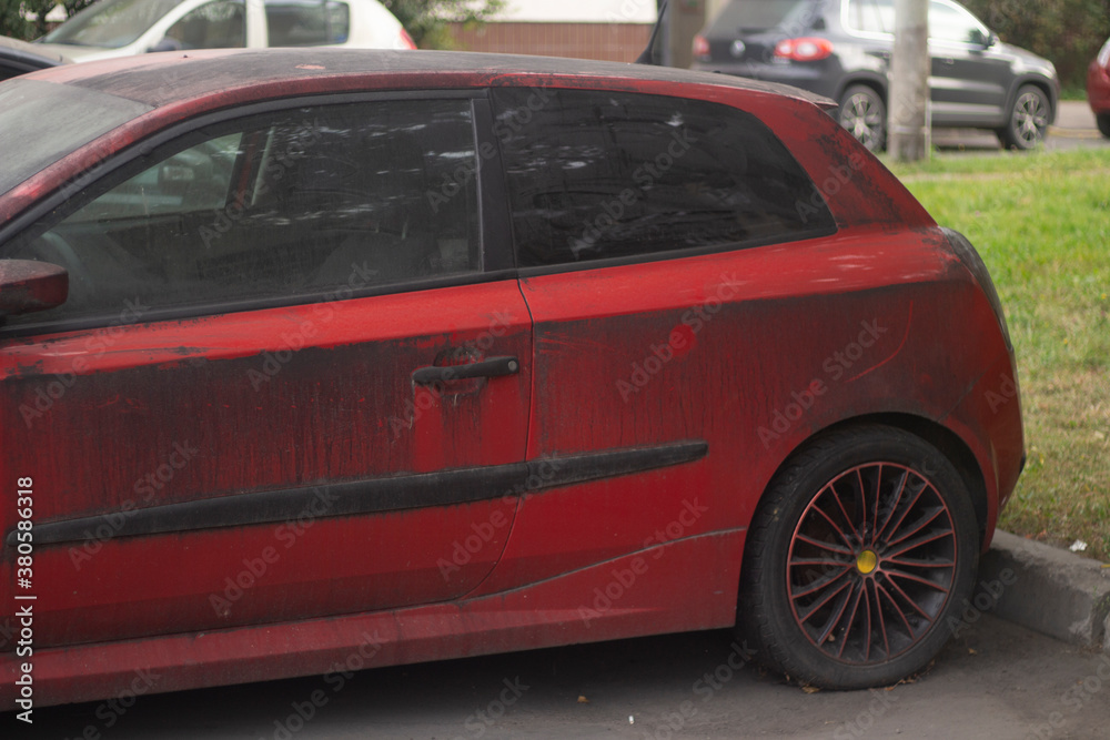 Dirty and broken red car. The car is abandoned in the parking lot ...