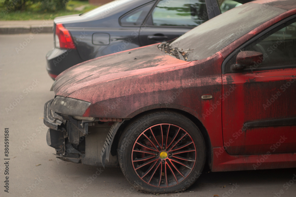 Dirty and broken red car. The car is abandoned in the parking lot ...