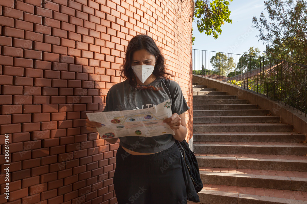 Young spanish empowered woman wearing protective mask using a map on a ...