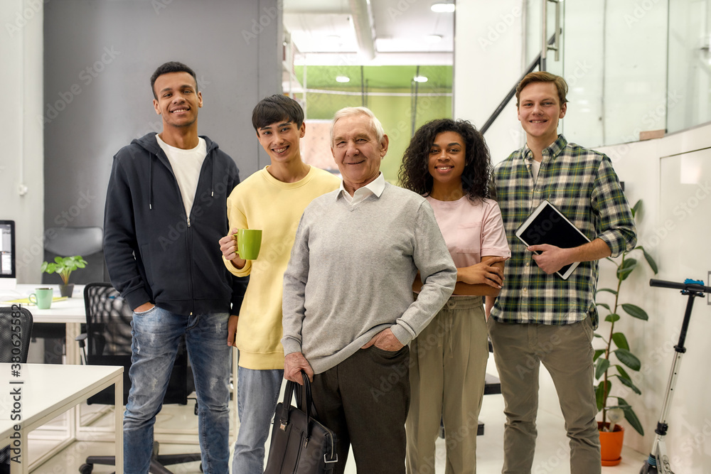 Happy diverse team of employees looking at camera while posing with ...