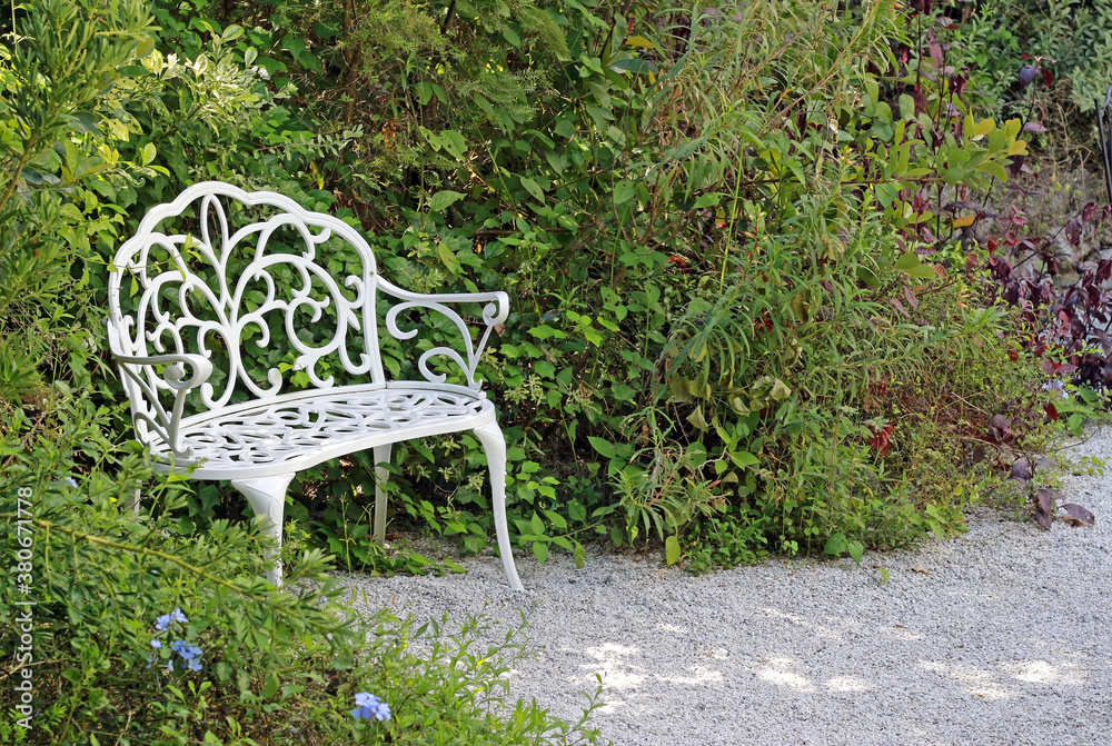 Classical decorative white wrought iron garden bench at the side of a ...