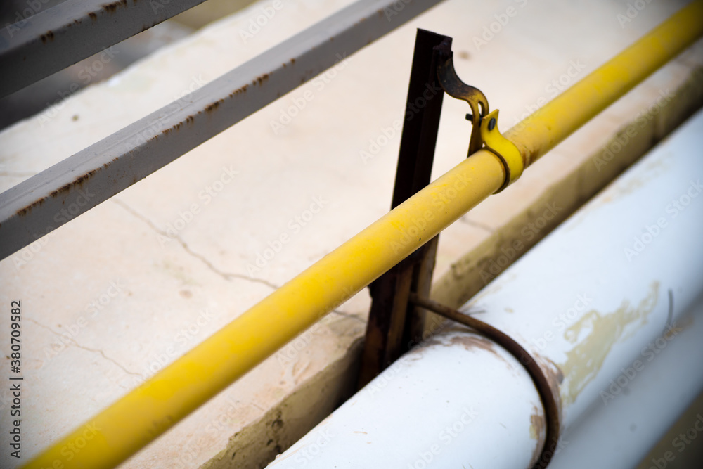 Narrow yellow pipe on top of a white piple going diagonally across the ...