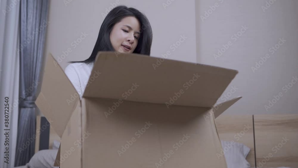 young asian woman sit down inside bedroom unpack brown parcel box ...