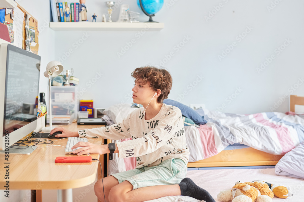 Teenage boy using computer in his room Stock Photo | Adobe Stock