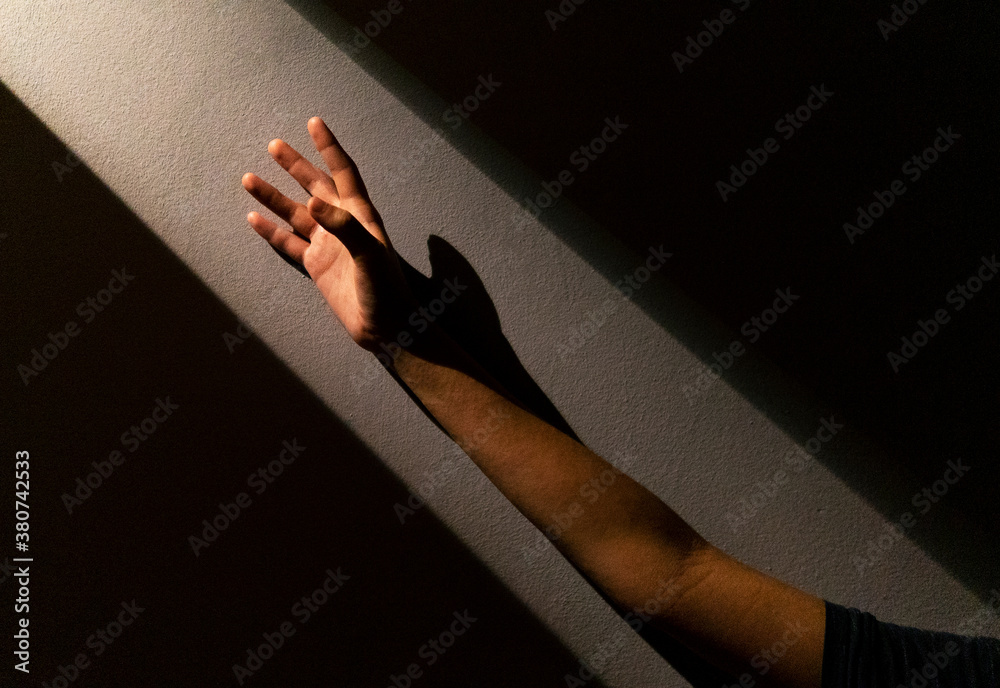 Unrecognizable crop person reaching out hand towards bright light while ...