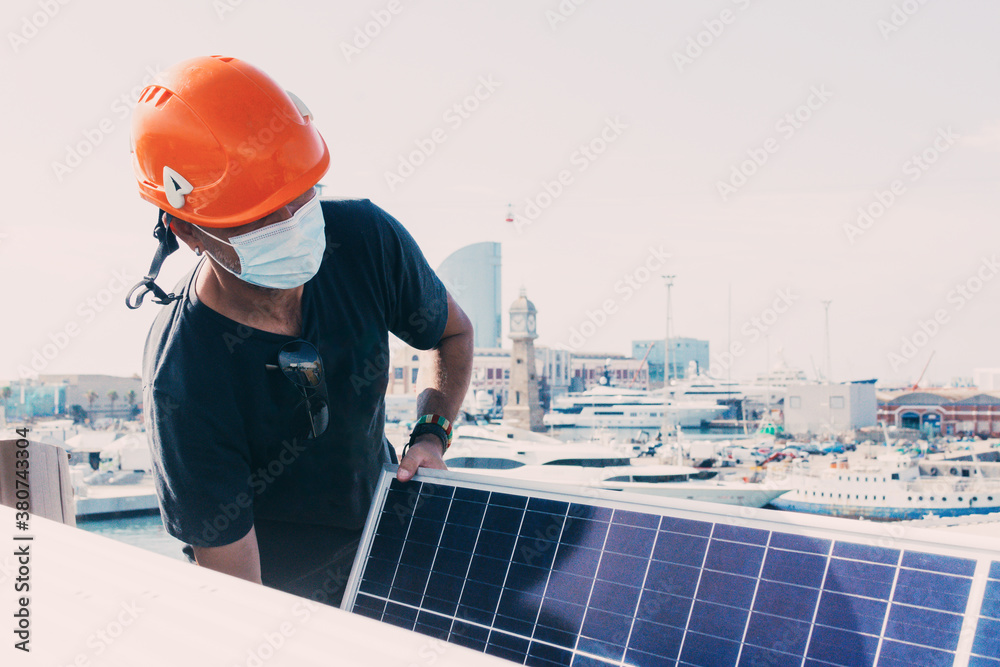 Black workman in helmet and protective mask installing solar battery in ...