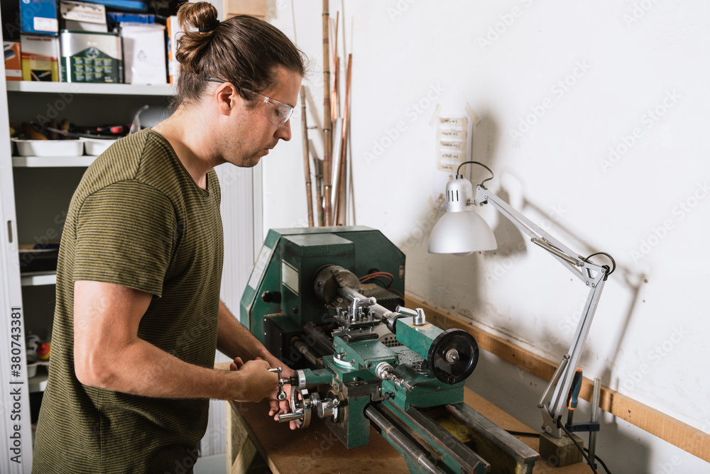 Handsome male woodworker standing at workbench and measuring detail ...