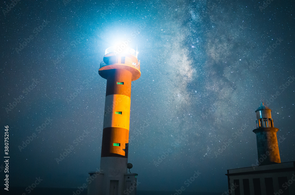 Low angle of lighthouse tower with glowing light against starry sky on ...