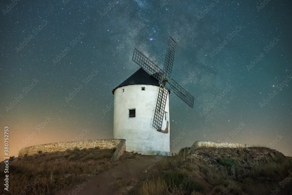 Low angle of old white windmill tower located on hill against starry ...