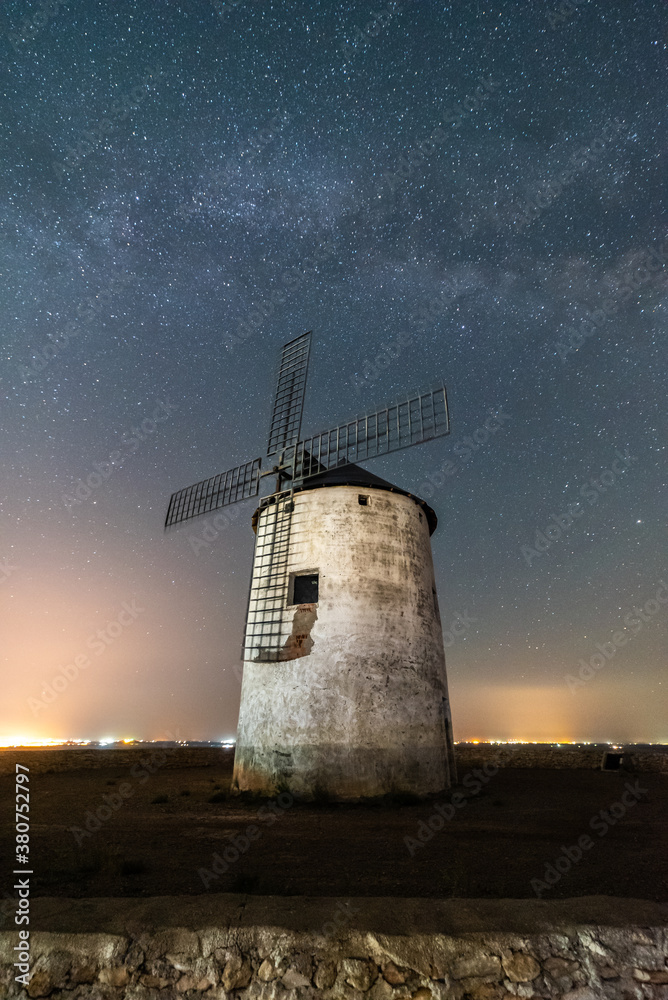 Low angle of old white windmill tower located on hill against starry ...