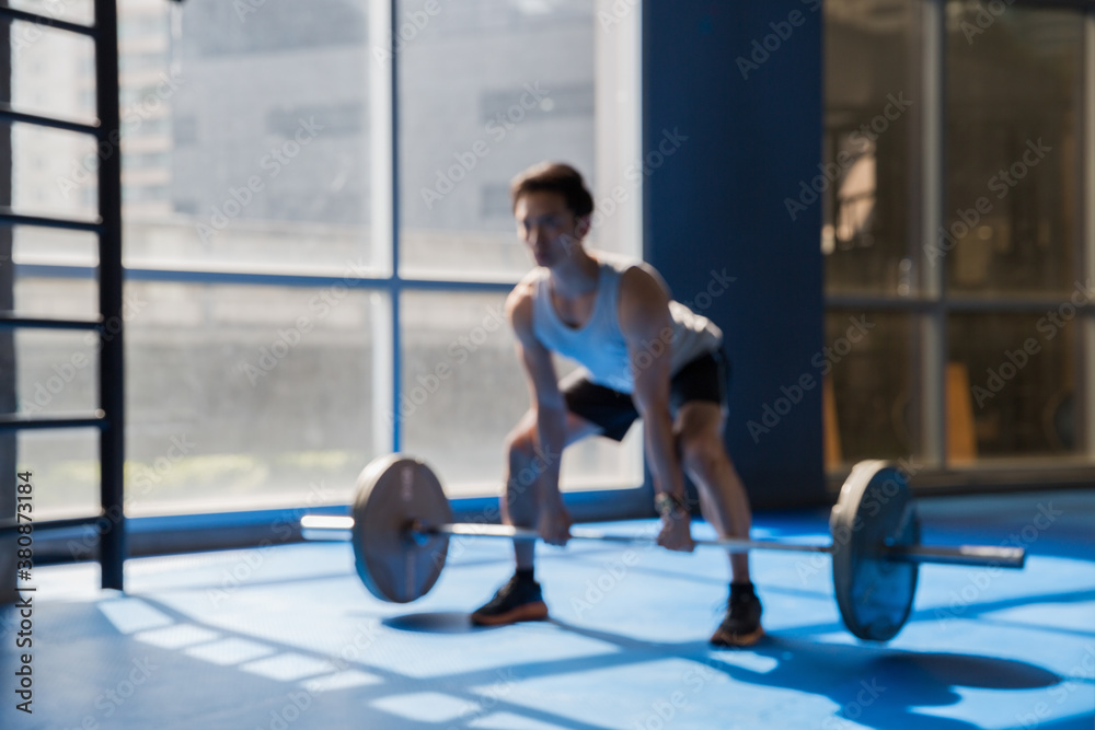 Short-haired fit man in his 20's prepares to lift weights in a gym ...