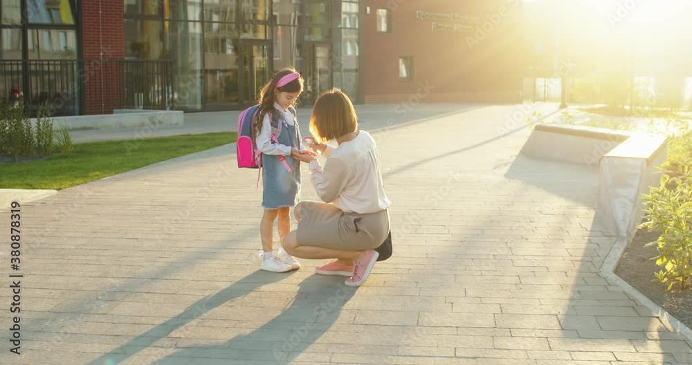 Caucasian beautiful woman meets little pretty girl from school on sunny ...