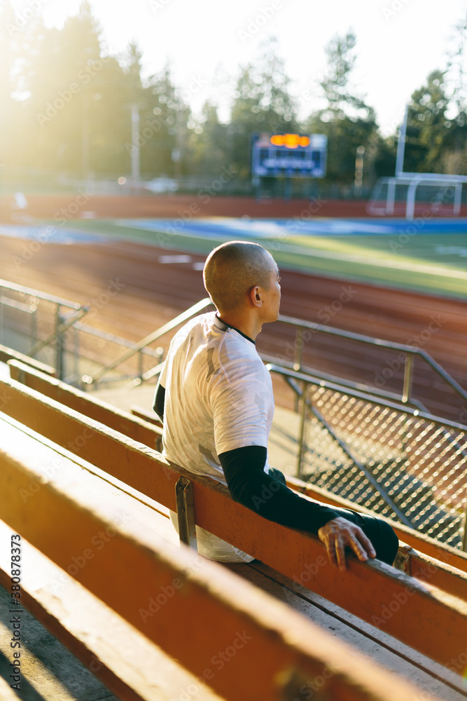 Athletic Man Sitting In Bleachers Looking Over Track And Field At ...