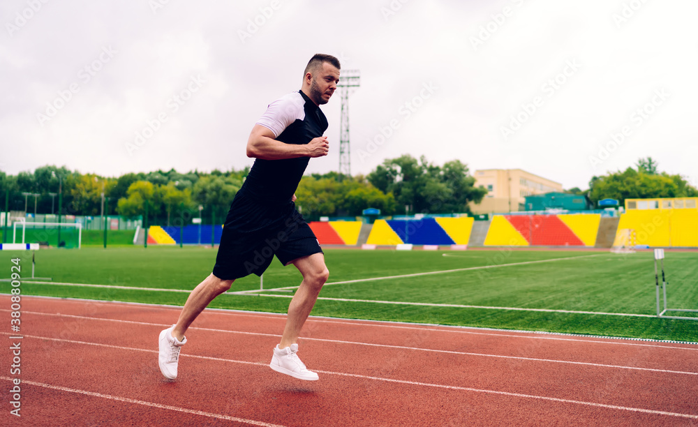 Strong determined handsome guy in active wear jogging outdoors on ...