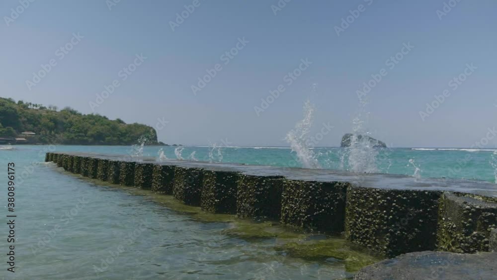 Waves create sea spray against a concrete beach pontoon in Bali. Stock ...