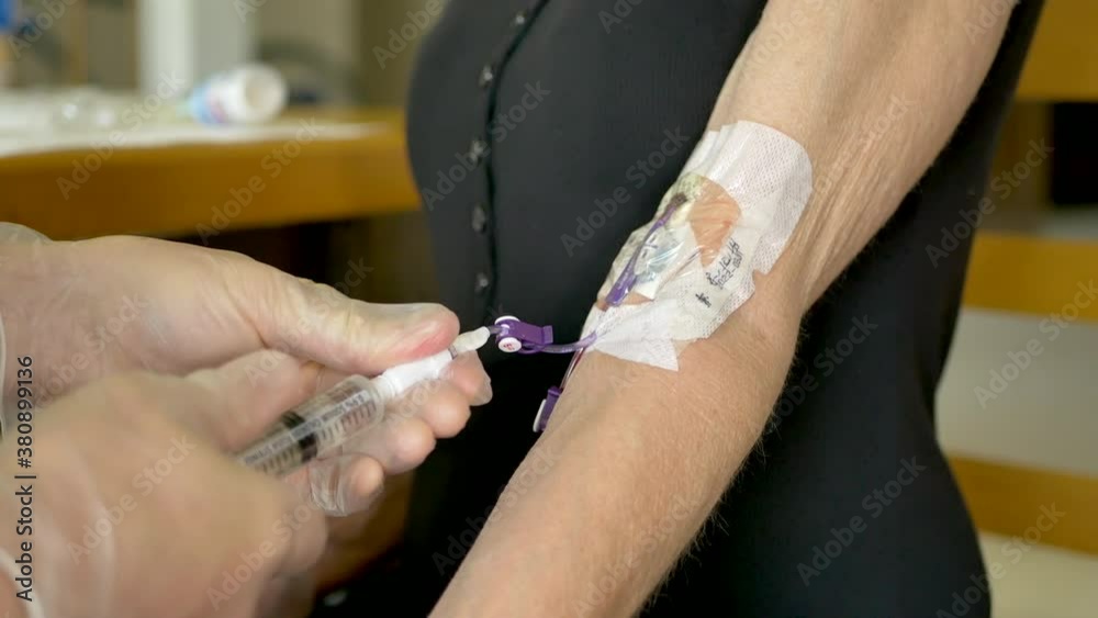 Medical nurse doing an at home iv patient visit wearing sterile gloves ...