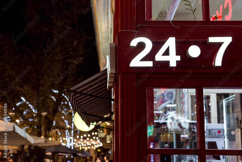facade of red shop on corner with luminous signboard 24/7 round the ...