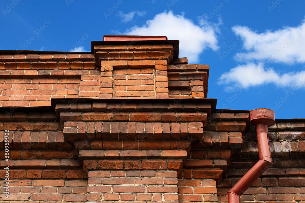 Old brick building, parapet on the roof of an against a blurred ...