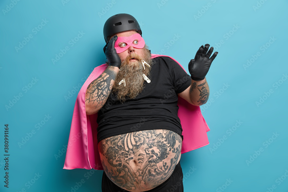 Frightened coward bearded man in superhero costume spends laisure time ...