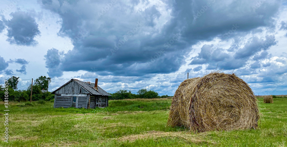 Rural landscape with harvesting field, hayroll and small old house ...