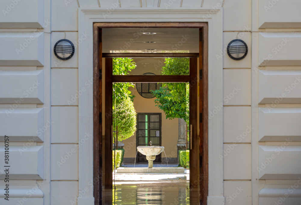 Inner courtyard with a fountain and trees seen from the outside of the ...