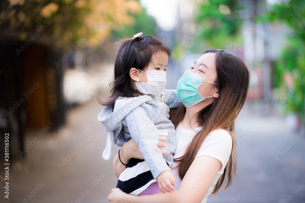 Family carried child. Mother and daughter wear medical face mask. Mom ...