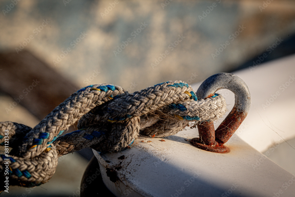 A close up of boat ropes tied up around the cleat of a wooden boat ...