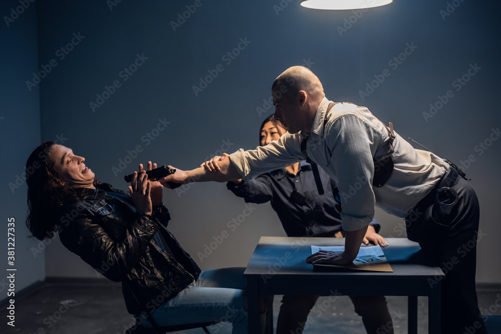 Violence by a police officer against a suspect in an interrogation room. An officer threatens a ...