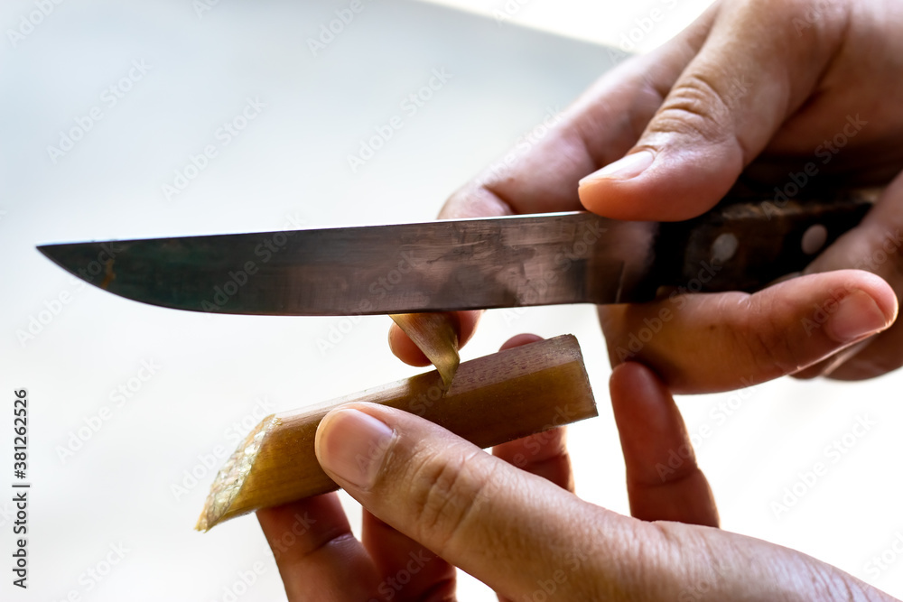 hand holding a knife peeling lotus stem for cooking. Lotus stem or ...
