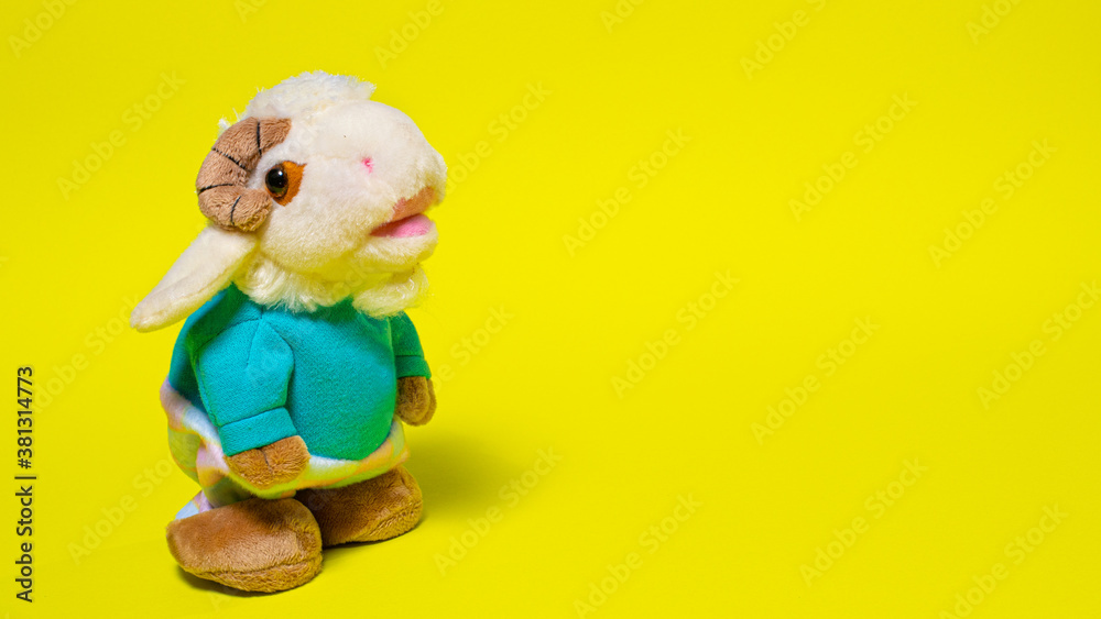 Toy plush soft lamb ram sheep in clothes on a yellow background. Baa ...