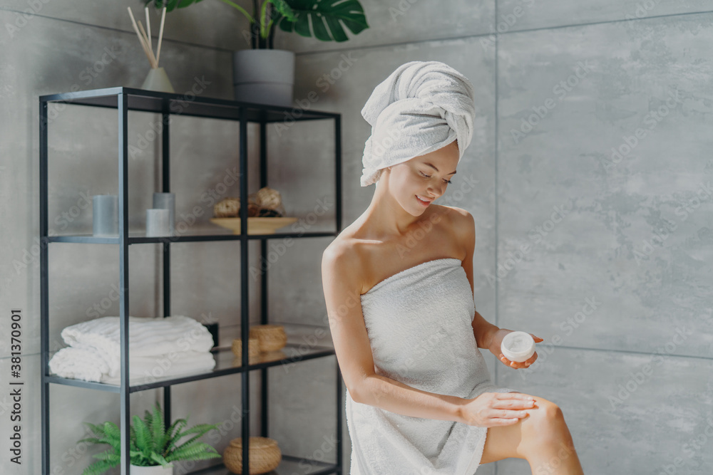 Body care concept. Lovely female model applies moisturising cream on ...