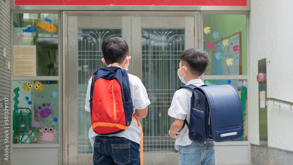 Two little boys with backpack are walking into the school. School kids ...