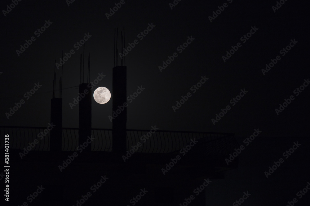 silhouette of a building pillars against the super moon also called big ...