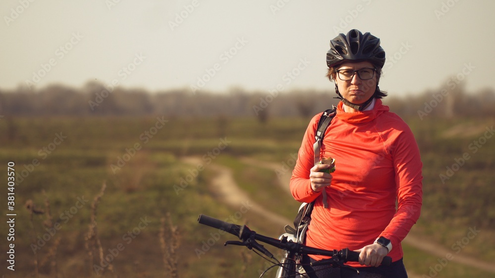 Athletic Caucasian woman eats protein bar ride on mountain bike on ...