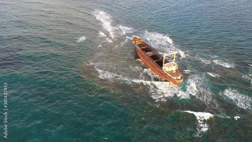 The sunken rusty ship has been lying on the rocks for many years. The ...