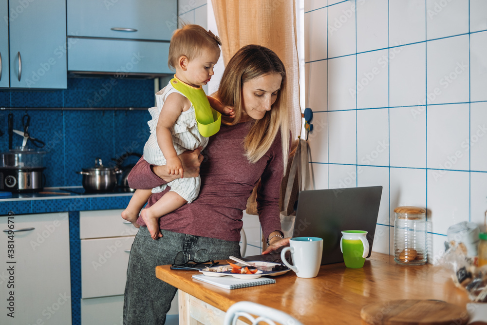 Work from home. Young mother with baby girl working at home using ...