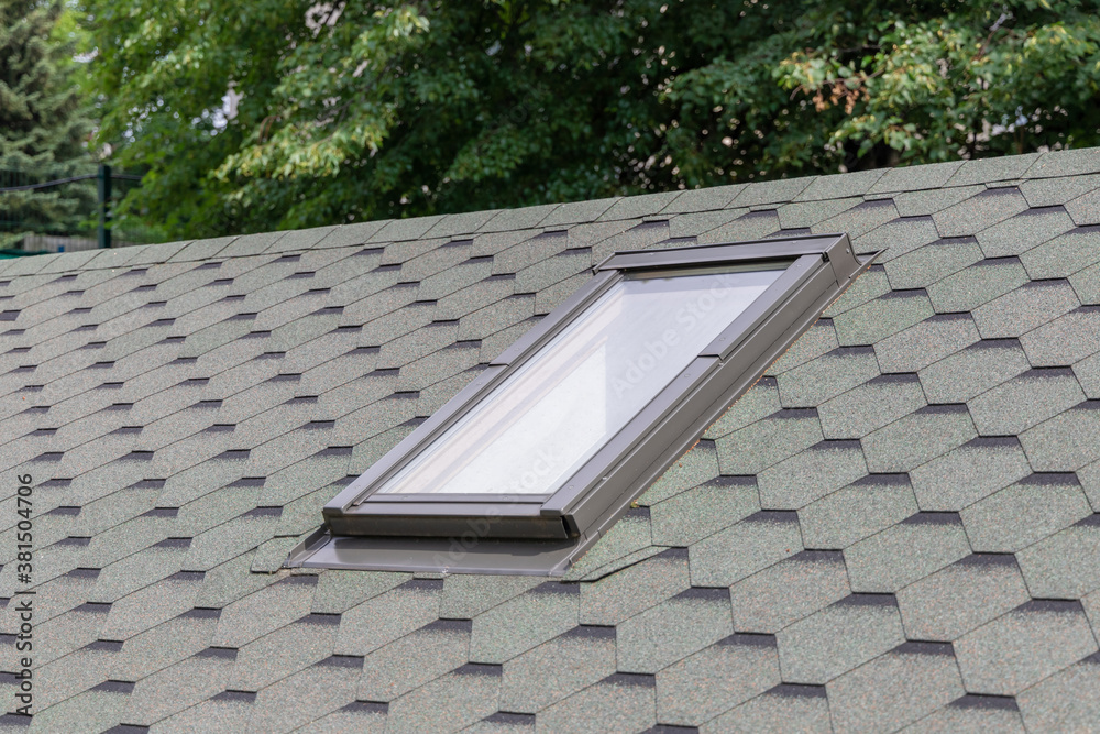 Sloping roof of house with narrow window and covered with flexible ...