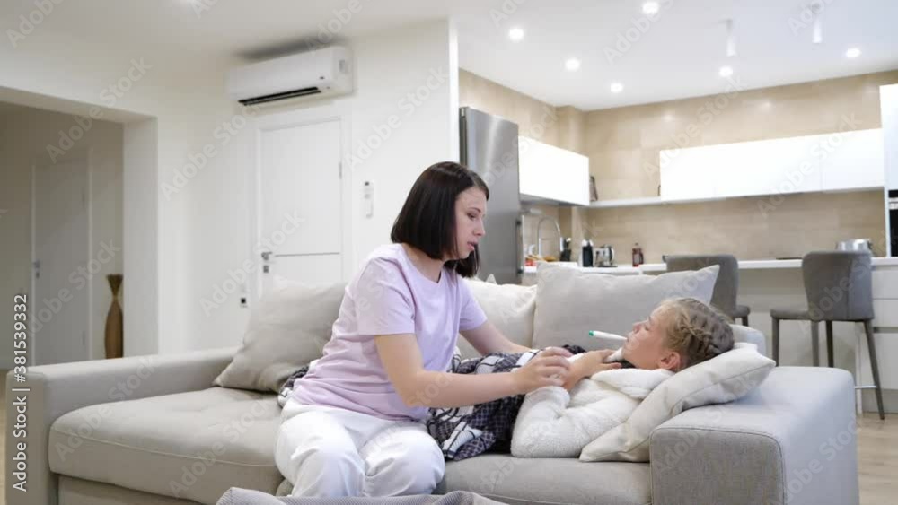 mother caring for sick child lying in bed with flu measuring temperature using thermometer ...