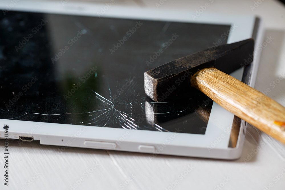 The hammer hits the broken touchscreen tablet, suggesting that it is ...