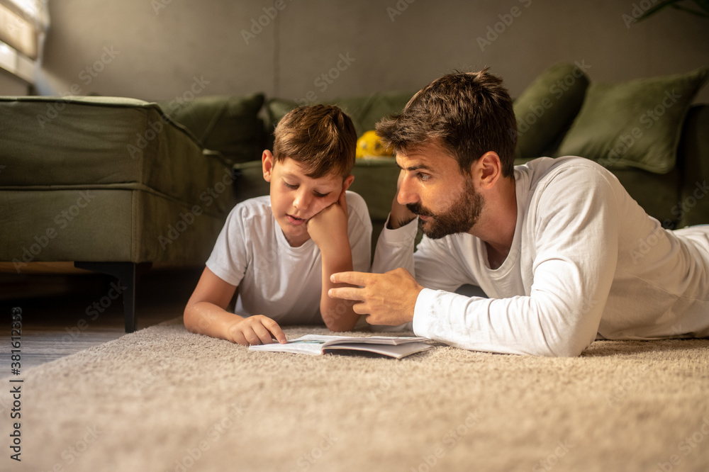 Father and son lying together in the living room on the floor and ...