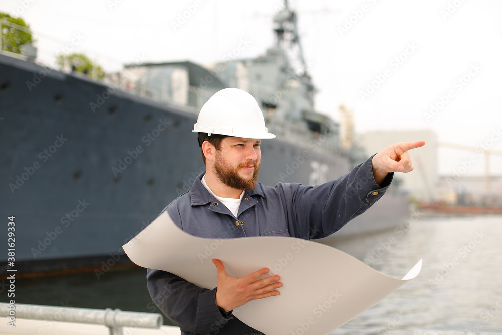 Maritime captain reading blueprints, showing by forefinger and standing ...