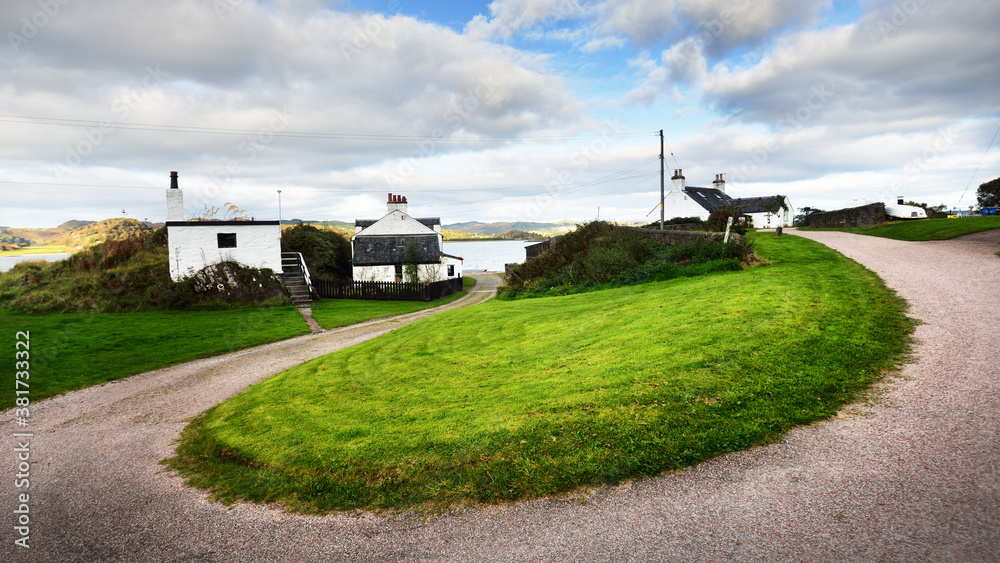An empty country road and small traditional house on the rocky shore of ...