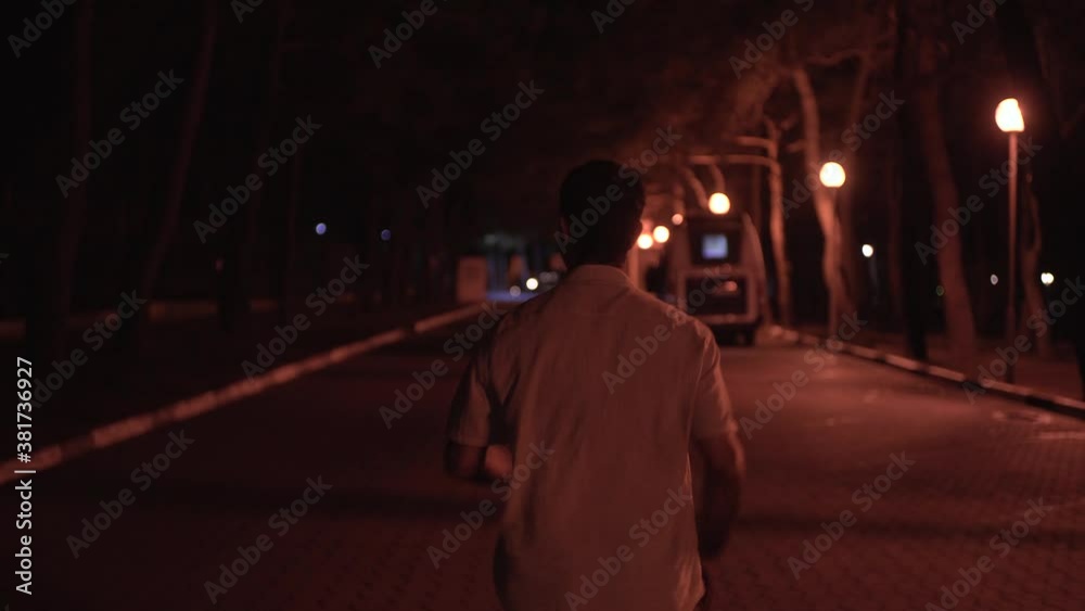 Man running through city at night. Media. Back view of man running in ...