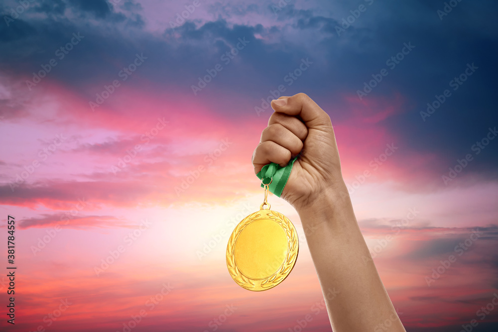 Winner raising hand with gold medal up to sunset sky, closeup Stock ...