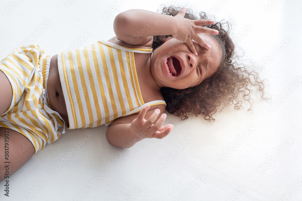 Dark skinned child girl crying and shouting with tantrum lying on the ...