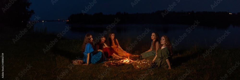 Lovely girls by the fire at night. Ancient pagan origin celebration ...