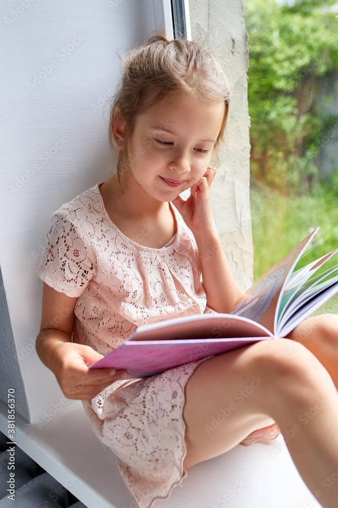 Cute little girl reading book at home, at windowsill Stock Photo ...