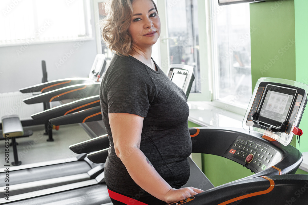 Fat woman fights overweight in the gym, doing heavy fitness exercises ...